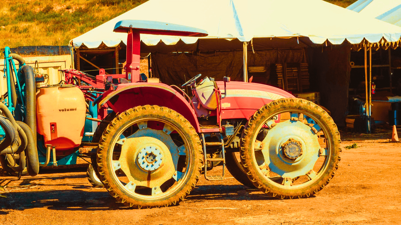 A tractor parked in front of a shipping container and large tent ...